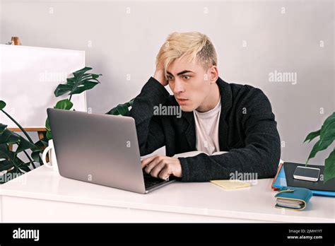 A Young Frustrated Shocked Man Holds On To His Head Staring At A