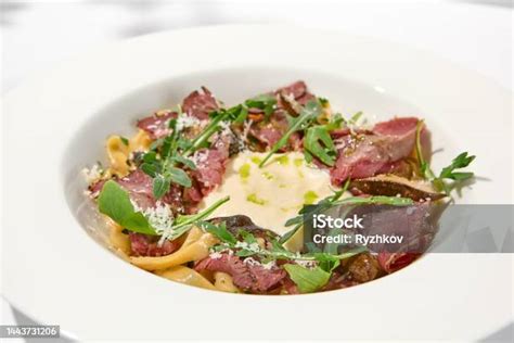 파스타 라미와 치즈와 크림 소스를 곁들인 수제 파스타 흰 테이블에 쇠고기와 소스를 곁들인 이탈리아 파파델 햇볕의 그림자가있는
