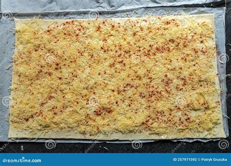 Raw Puff Pastry Sprinkled With Grated Cheese And Powdered Paprika Stock