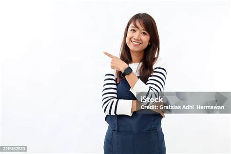 행복 한 아시아 바리 스타가 손가락을 옆으로 가리키고 웃고 푸른 앞치마 유니폼을 입고 흰색 배경에 서 있습니다 공간 복사 35 39세에 대한 스톡 사진 및 기타 이미지
