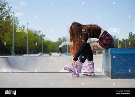 Cool Young Skater Female Putting On Aggressive Inline Skates In A Concrete Skatepark Athlete