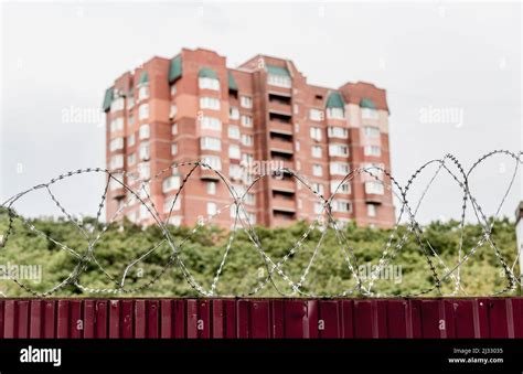 Barbed Wire On Fence With Modern Residential Building On Background Protection And Prohibition