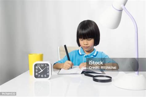 귀여운 아이가 쓰기 작업 책상에 노력 하 고입니다 아시아 아이 여자 활성 및 작업에 대 한 지혜 이다 그녀는 흰색 회색 직물 배경에의 자에 앉아 감정에 대한 스톡 사진 및