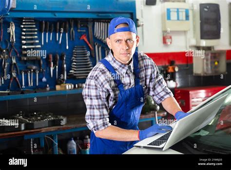 Male mechanic using laptop while repairing car in service Stock Photo - Alamy