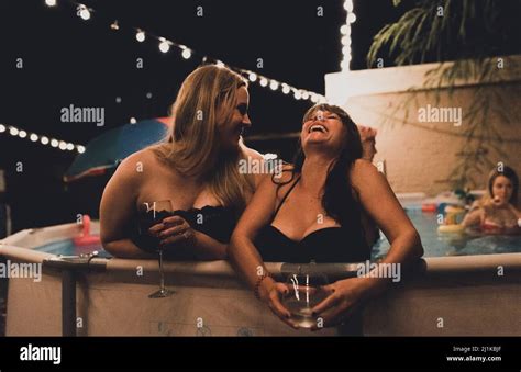 Friends At A Pool Party Drink Wine And Laugh Outside At Night Stock
