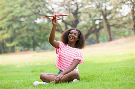 야외에서 장난감 비행기를 가지고 노는 웃는 아프리카계 미국인 소녀 공원에서 장난감 비행기를 가지고 즐거운 시간을 보내는 아이 행복한 흑인들 교육 및 견학 개념 10 11세에