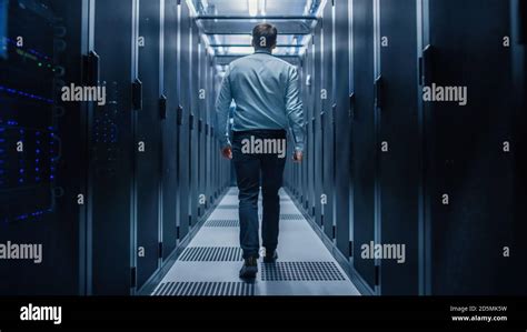 It Engineer Walking Through Data Center With Working Server Rack To Do Routine Maintenance Check
