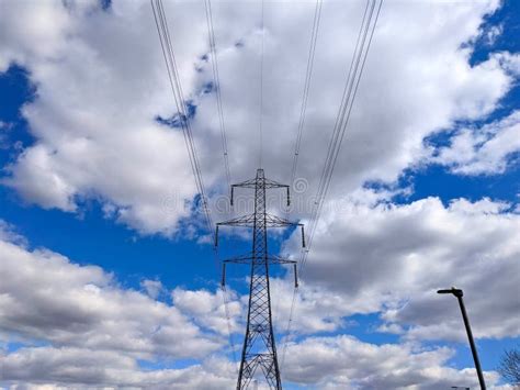 A Tall Steel Lattice Electricity Pylon And High Voltage Power Lines Stretching Across A Blue Sky