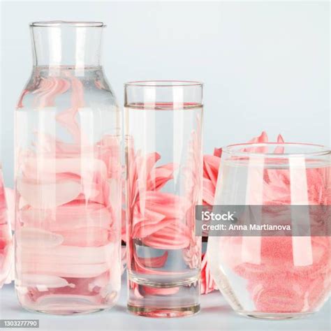 분홍색 꽃은 파란색 배경에 안경과 병에 물을 통해 왜곡 홈 장식 환경 친화적 인 휴식 원예 개념 복사 공간을 복사합니다 사각형