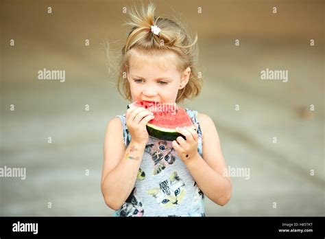 Adorable Blonde Girl Eats A Slice Of Watermelon Outdoors Stock Photo Alamy