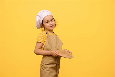 귀여운 작은 요리사 과자 장수 요리사 제빵사 피자이올로 사랑스러운 꼬마 소녀가 나무 판자를 들고 카메라에 미소를 짓고 있다 6 7 살에 대한 스톡 사진 및 기타 이미지