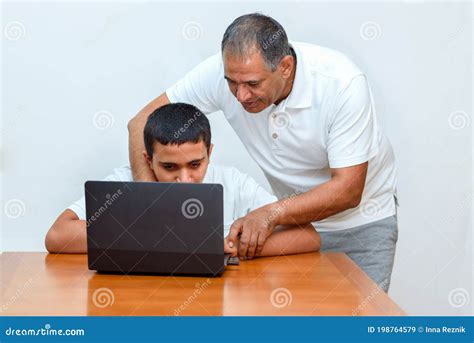 Senior Father And Teenage Son Using Laptop Babe And Dad Sitting At Home Working With Tablet
