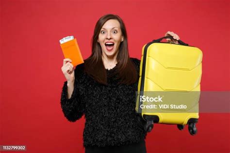 빨간 배경에 고립 된 입 지주 가방 여권 탑승권 티켓을 열어 검은 모피 스웨터에 놀란 젊은 여자 사람들은 진심으로 감정 라이프 스타일 개념입니다 복사 공간을 모의 합니다