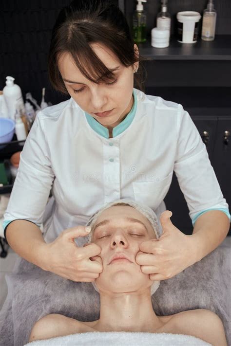 A Female Cosmetologist Gives A Facial Massage To A Young Man Beauty