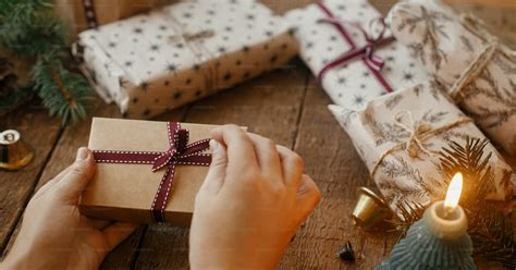 양초 가위 전나무 가지가 있는 소박한 나무 테이블에 세련된 크리스마스 선물을 여는 손 즐거운 성탄절 세련된 스칸디나비아 크리스마스 선물 분위기 있는 변덕스러운