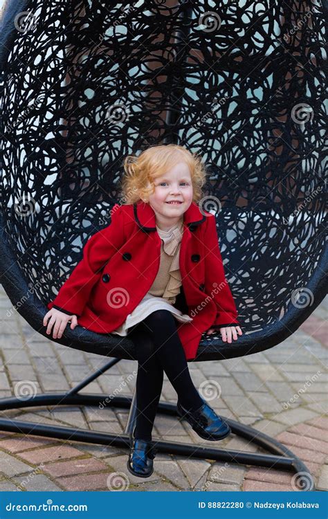 Retrato De Uma Menina Bonita Com Cabelo Vermelho Em Um Revestimento Vermelho Foto De Stock