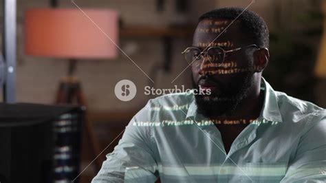 African american programmer in glasses working on computer, program code reflecting on him. Dark ...