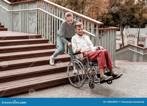 Strong Woman Helping Invalid Man And Carrying His Wheelchair Royalty