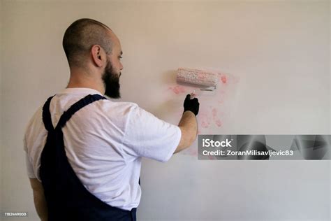 아파트에서 마무리 리노베이션을하고 건설 노동자 건설 현장에 콘크리트 벽실의 흰색 페인트 롤러 브러시 그림을 사용하여 전문 화가 계약자 홈 리노베이션 개념입니다 건설 산업에