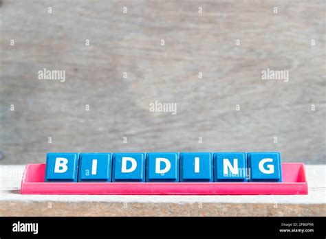 Tile Alphabet Letter With Word Bidding In Red Color Rack On Wood