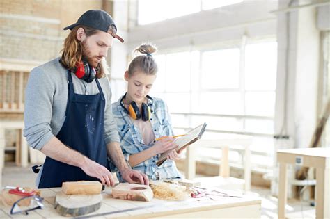 진지 하 게 집중 된 소식통은 모자에 책상에 서 있는 뚜껑을 하 고 전시 인턴 나무와 함께 작업 하는 방법 젊은 여자 나무를