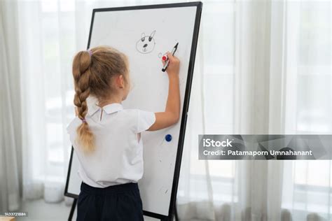 앞 수업에 서서 복사 공간이있는 흰색 보드에 검은 펜으로 그림을 그리는 젊은 백인 예쁜 소녀의 뒷모습 학교에서 수업 중에 자신