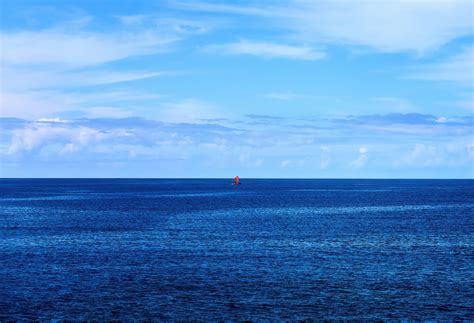 낮 동안 푸른 하늘 아래 푸른 바다에 서 있는 빨간 셔츠를 입은 사람 사진 Unsplash의 무료 빨강 이미지