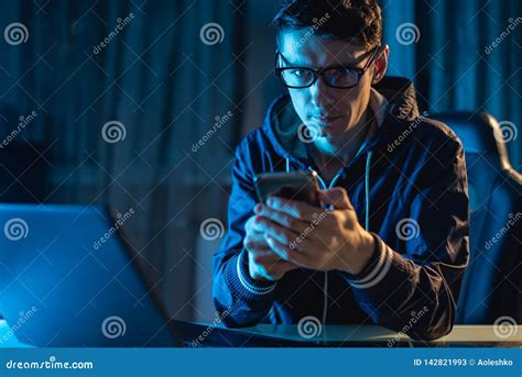 Male Hacker Holding The Phone In His Hands And Trying To Steal Access Databases With Passwords