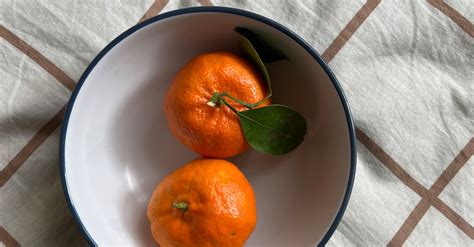 체크 무늬 원단 위에 놓인 흰색 그릇에 담긴 신선한 귤 · 무료 스톡 사진