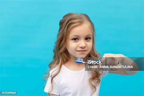 흰색 티셔츠를 입은 귀여운 어린 소녀는 파란색 배경에 칫솔로 이빨을 닦고 위생과 치과의 개념 텍스트 공간 아이에 대한 스톡 사진 및 기타 이미지 Istock