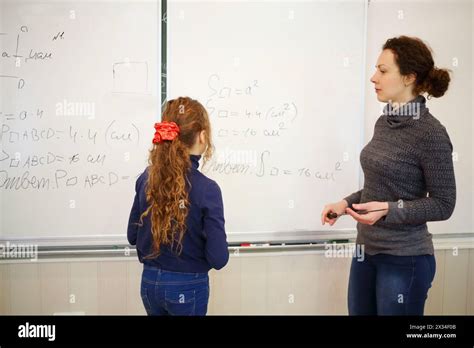 Schoolgirl And Teather Stand Near Blackboard With Geometry Example In