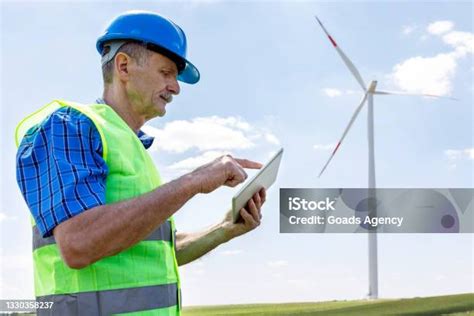 풍력 터빈과 디지털 태블릿을 사용하여 현장에 서 있는 엔지니어 60 64세에 대한 스톡 사진 및 기타 이미지 60 64세