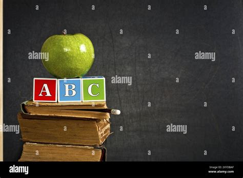 Abc And Green Apple On Old Textbook Against Blackboard In Class School