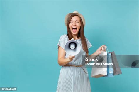 여름 드레스에 세로 여자 모자 패키지 가방을 들고 블루 파스텔 배경에 고립 된 할인 판매 발표 구매 후 쇼핑 확성기에서 비명 광고에 대 한 공간을 복사 합니다 가방에 대한