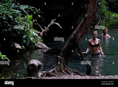 Tourists Bath In The Shallow Lagoon Of Sai Ngam Hot Springs Surrounded By A Lush Forest Near The