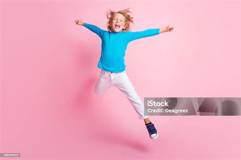 작은 소년 점프 스타 포즈의 전체 길이 사진은 블루 터틀 넥 바지 운동화 고립 파스텔 핑크 컬러 배경 아이에 대한 스톡 사진 및