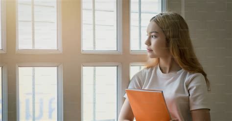 젊은 아시아 여자 학생이 교실 창가에 서서 책을 들고 있다 사진 Unsplash의 한 사람 이미지