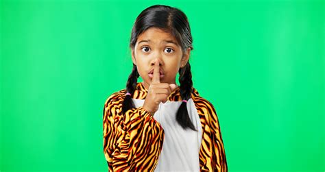 비밀스런 그린 스크린과 조용한 제스처를 위해 입술에 손가락을 대고 있는 스튜디오에 있는 아이의 얼굴 소음 젊은이 그리고 어린 아이의 초상화는 크로마 키 배경으로 침묵 또는