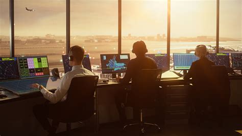 일몰의 현대 공항 타워에서 일하는 다양한 항공 교통 관제 팀 사무실 방은 네비게이션 화면 컨트롤러에 대한 비행기 비행 레이더 데이터와 데스크톱 컴퓨터 디스플레이의 전체입니다