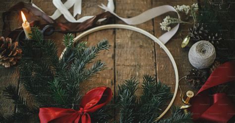 메리 크리스마스와 해피 홀리데이 촛불 리본 솔방울이 있는 소박한 나무 테이블에 전나무 가지와 빨간 활이 있는 현대 크리스마스 화환 분위기 있는 분위기 있는 이미지