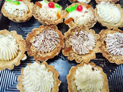 Assortment Of Cream Topped Tarts In A Display Case Rows Of Freshly