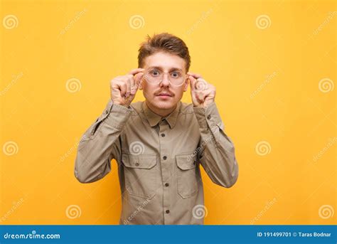 Portrait Of A Funny Nerd With Glasses And Mustache On A Yellow Background Looks Into The Camera