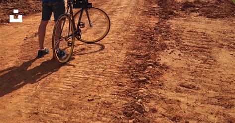 나무 근처의 비포장 도로에 서서 도로 자전거를 들고 있는 남자 사진 Unsplash의 무료 자전거 이미지