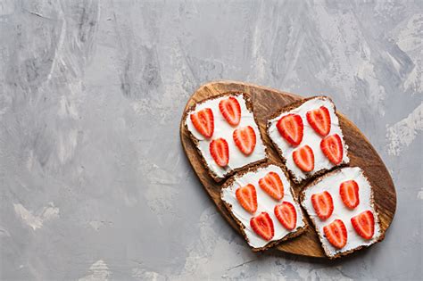 건강한 아침 식사 회색 콘크리트 배경에 딸기와 크림 치즈와 검은 빵 본격적인 라이프 스타일 이미지입니다 플랫 레이 복사 공간