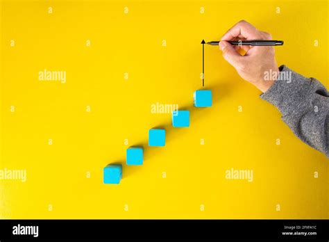 Man Hand Drawing An Upward Pointing Arrow On Top Of Growing Graph Made Of Wooden Block Over