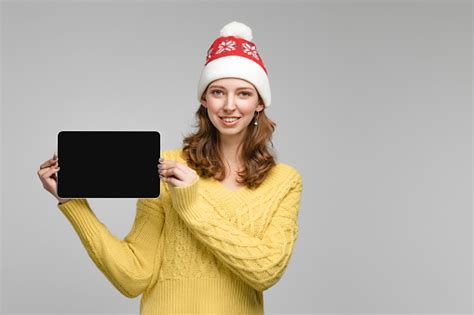회색 배경에 스튜디오에서 노란색 스웨터와 크리스마스 모자에 좋은 젊은 여성 태블릿과 개념 감정에 대한 스톡 사진 및 기타 이미지 Istock