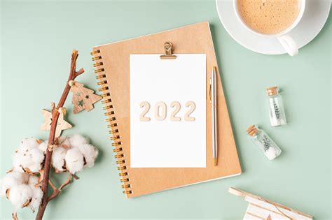 2022 텍스트와 상단 보기 데스크톱 크리스마스 메모장 플래너 커피 한 잔 나무 브런치 크리스마스 에코 자연 장식 노트북 및 문구와 녹색 민트 테이블 배경에 플랫 누워