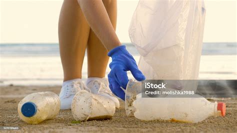 해변에서 플라스틱으로 모래 사장을 청소하는 여성 자원 봉사자들은 쓰레기 봉투에 쓰레기를 모은다 해양 플라스틱 오염 자연 환경 문제 개념 비어있는 더러운 플라스틱 병과 컵