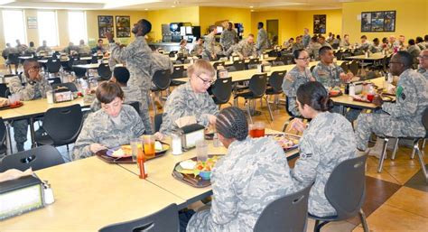 Several Soldiers Are Eating Lunch In A Large Room