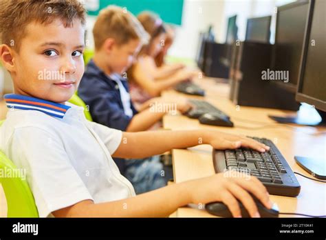 Side View Portrait Of Schoolboy Sitting At Desk With Friends In
